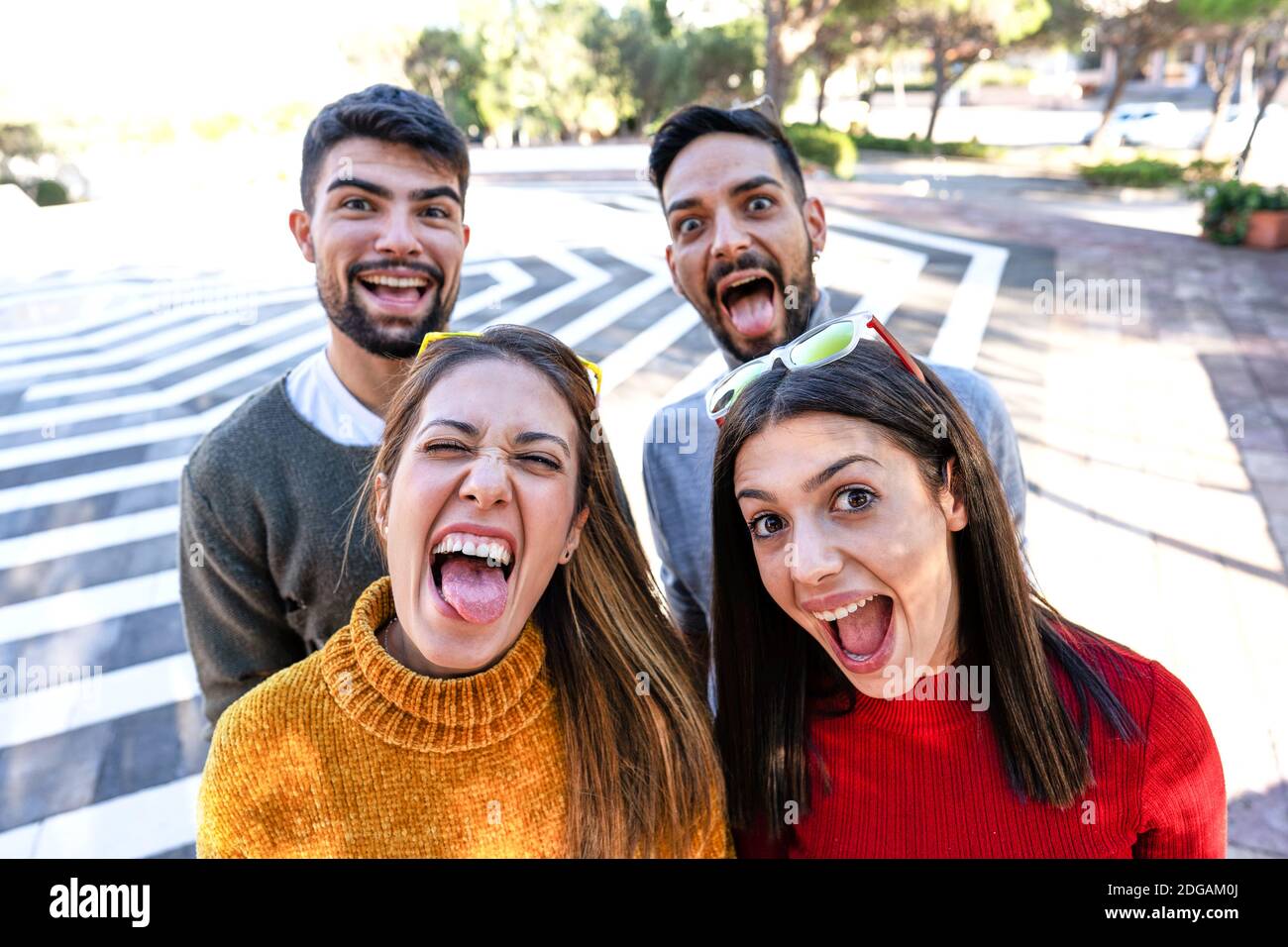 Two young millennial friends couple posing looking at the camera making ...