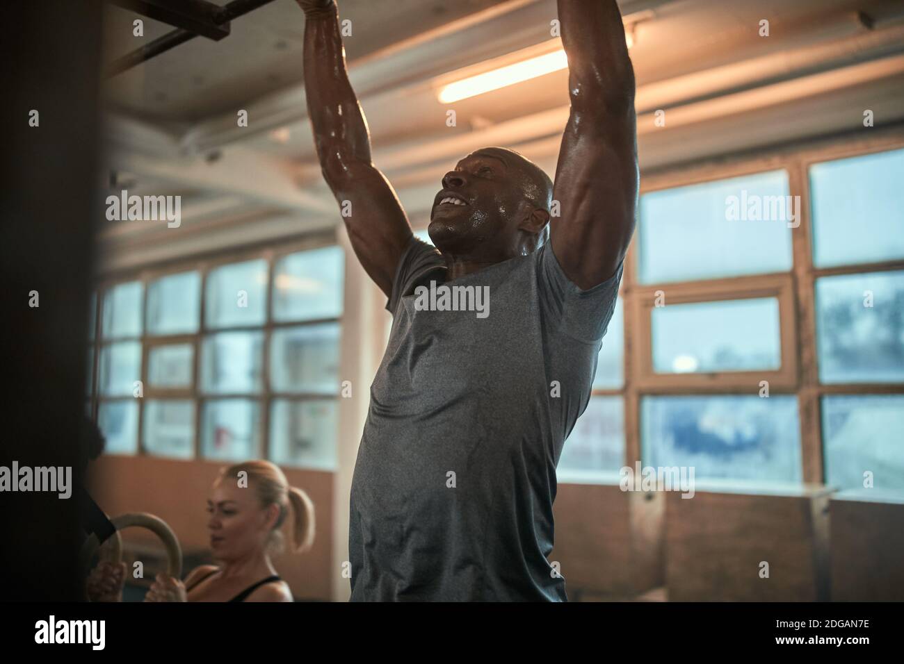 Fit young African American man in sportswear sweating while doing pull ...