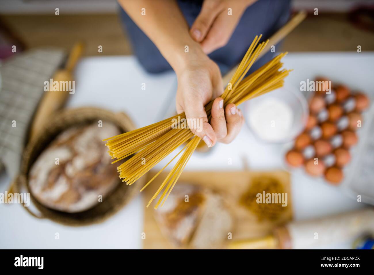 Female hand holding uncooked spaghetti above ingredients on a table ...