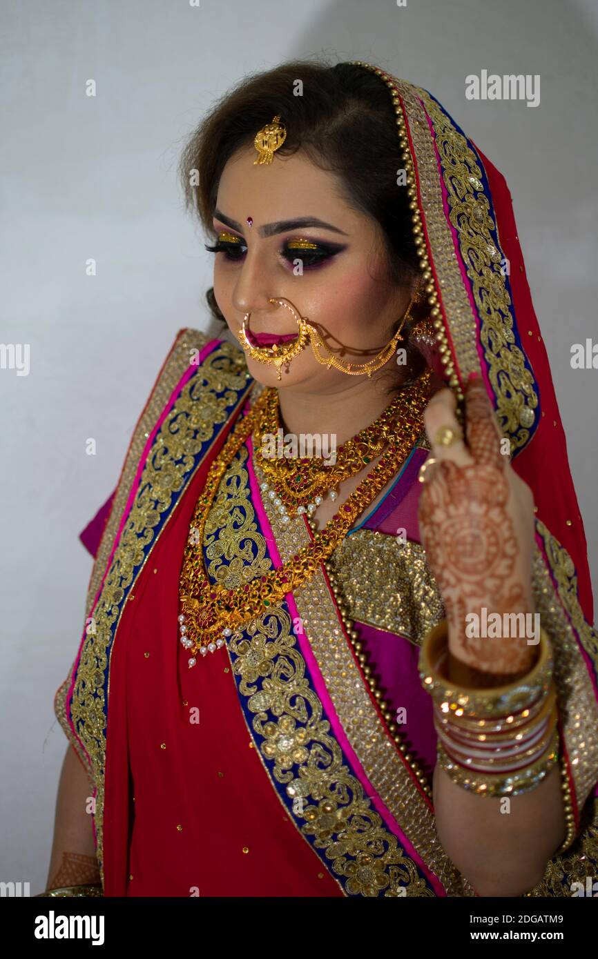 a beautiful Indian girl in bridal dress wearing red saree and gold ...