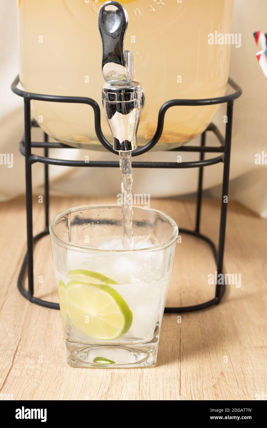 Man's hand pouring a glass of citrus juice into a beverage dispenser ...
