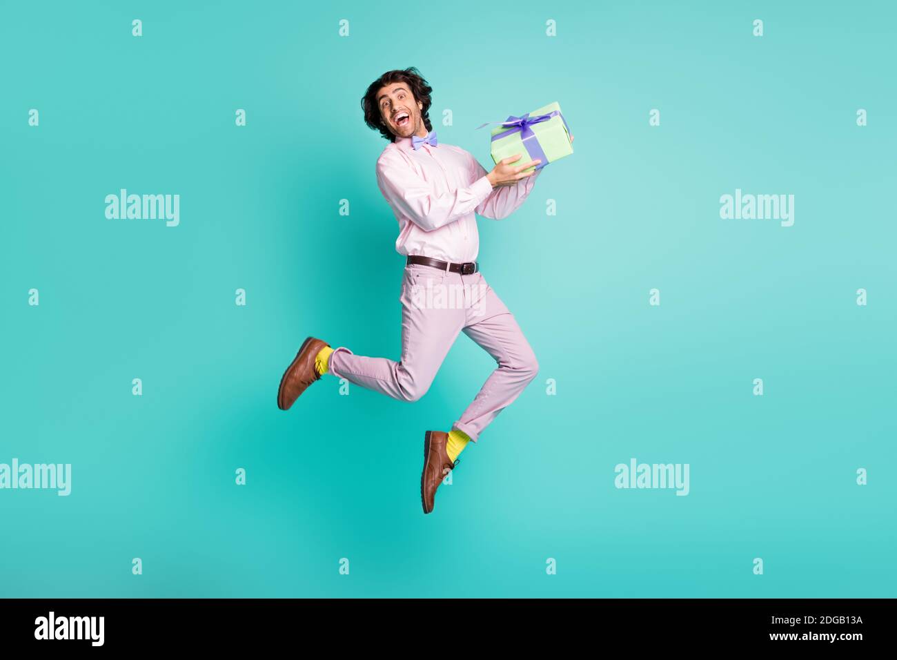 Full size photo of happy brunet hair young man jumping hold present ...