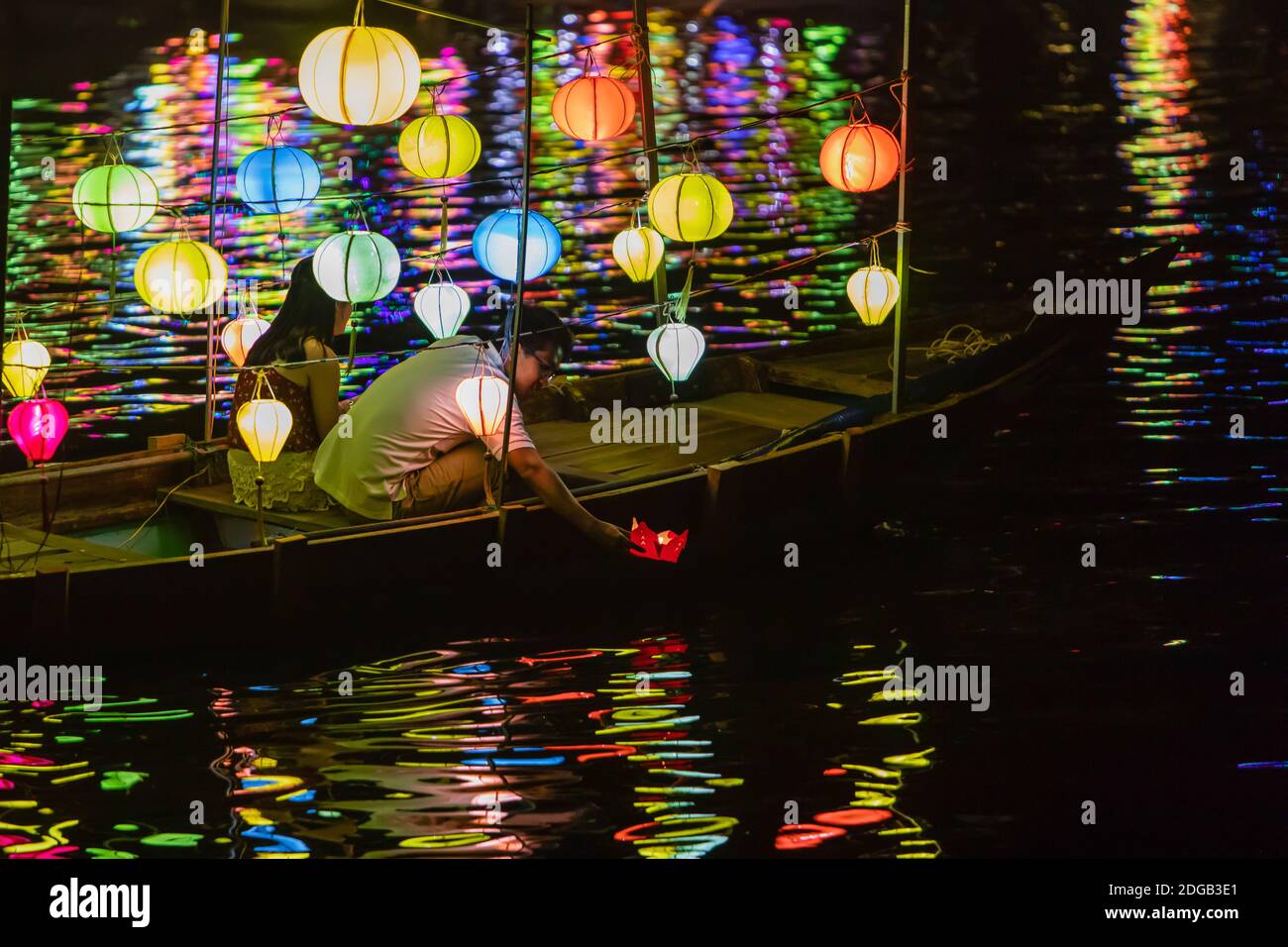 A man on a boat releases a lantern in the river during the Hoi An ...