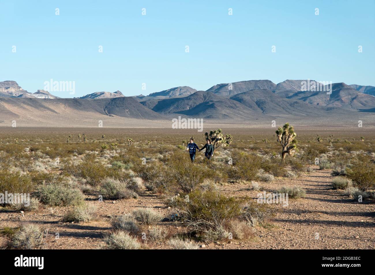 Couple walk in desert at Seven Magic Mountains, an artwork of limestone ...