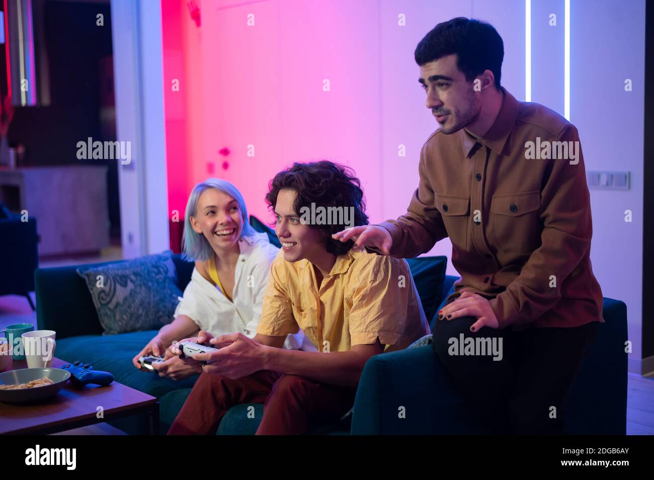 Happy young people playing video games on console while sitting on ...