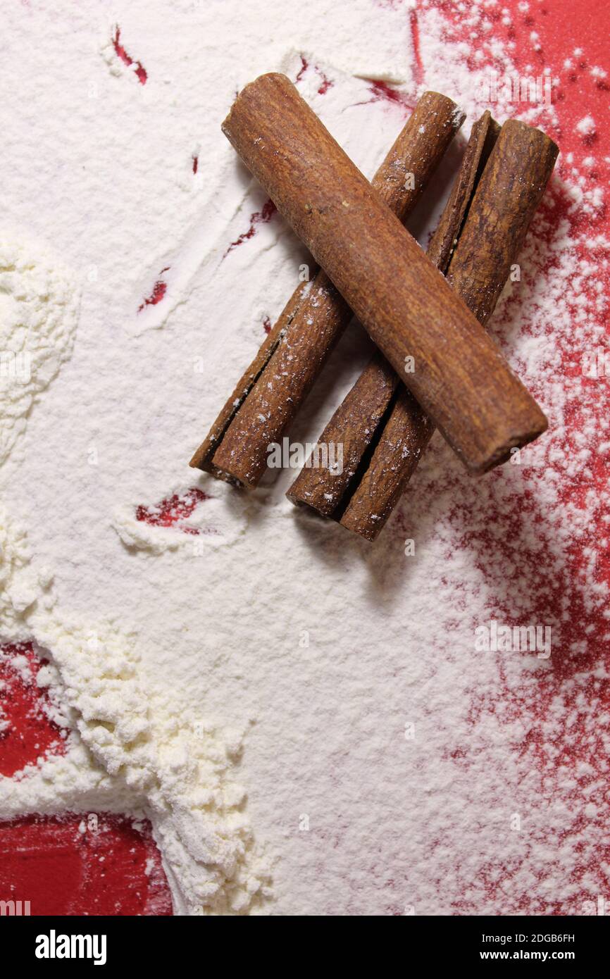 Three sticks of cinnamon lie on a white-painted background cooking a ...