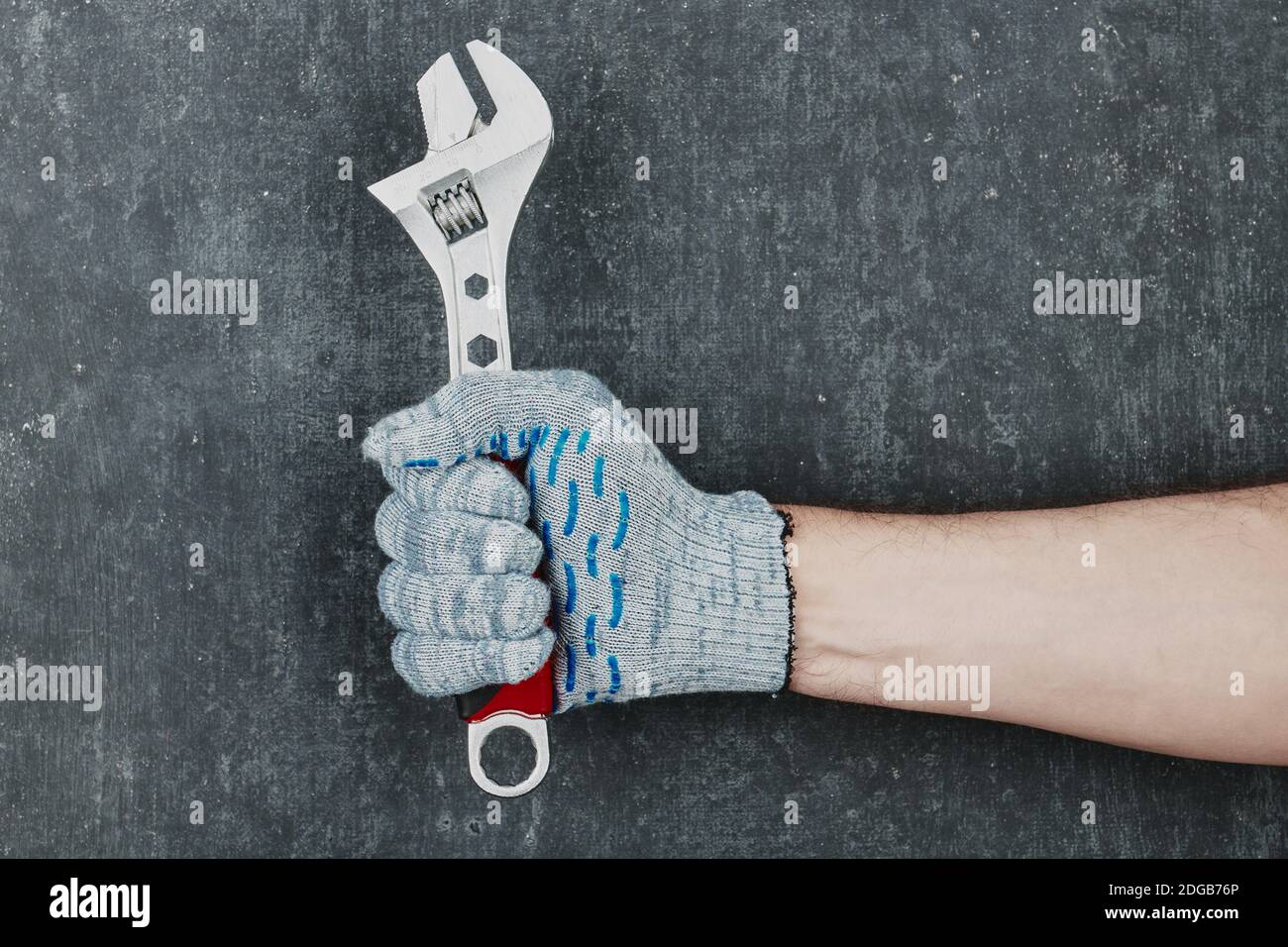 Man's hand holding an adjustable spanner wrench on gray background, man ...