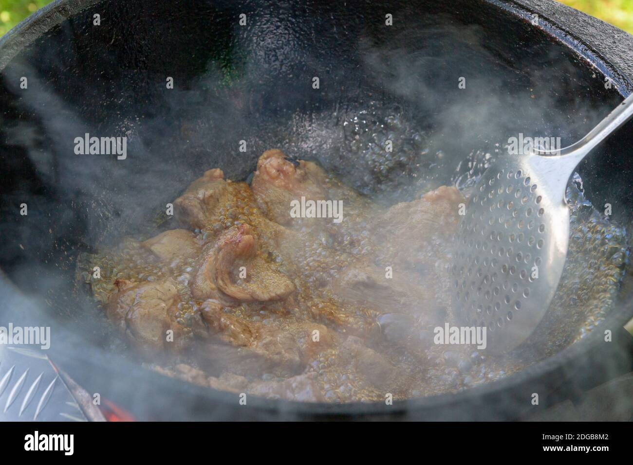 Cooking pilaf in a cauldron on the grill outside in the summer Stock ...