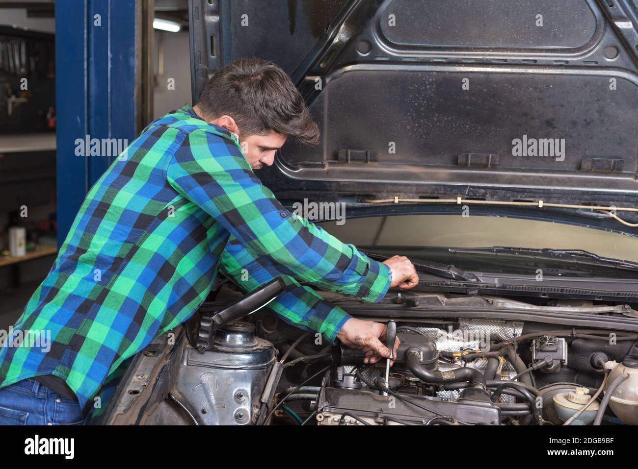 Handsome mechanic talking on the phone while repairing a car Stock ...