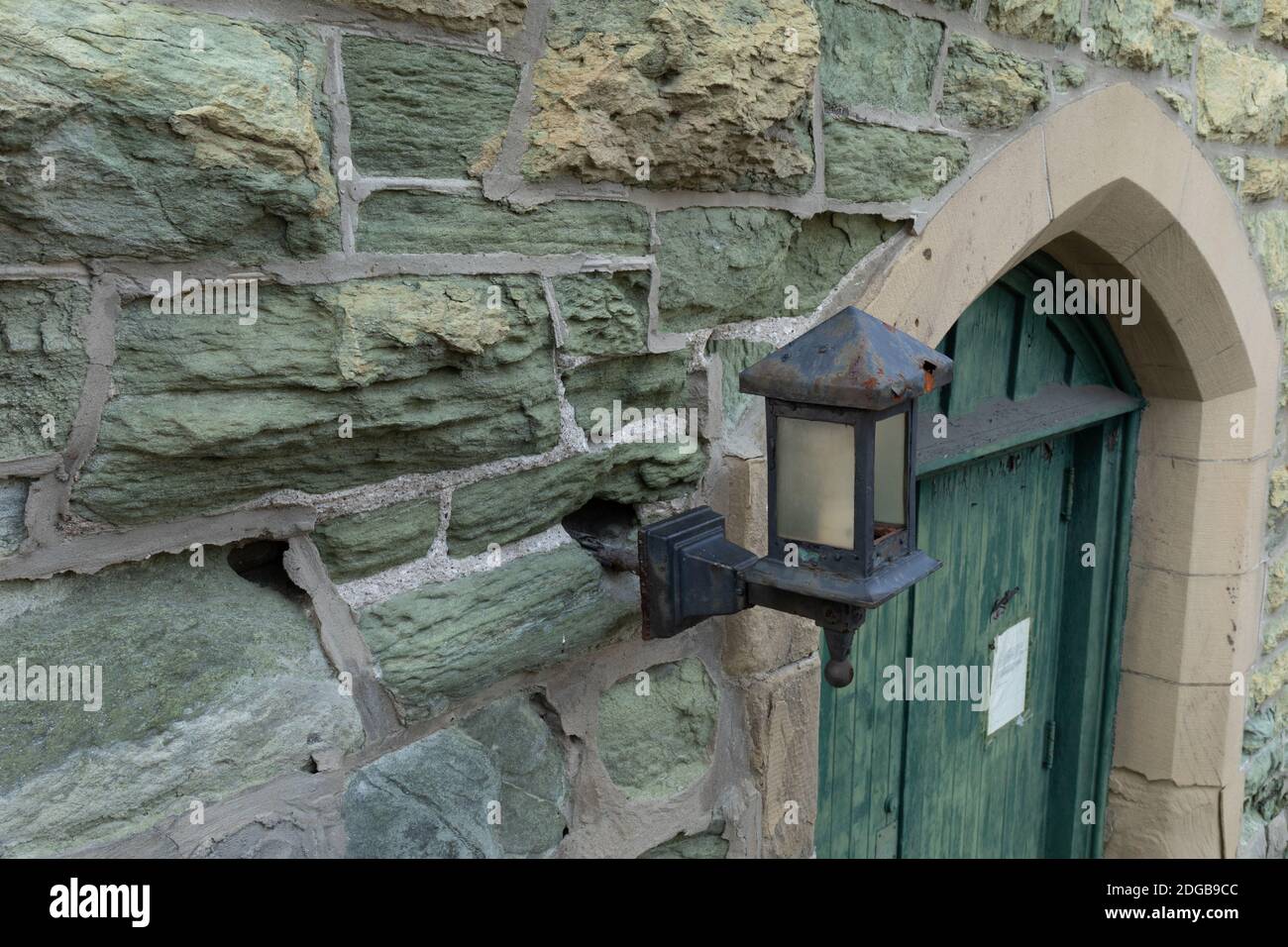 Crumbling green limestone wall, old metal lamp and green weathered door ...