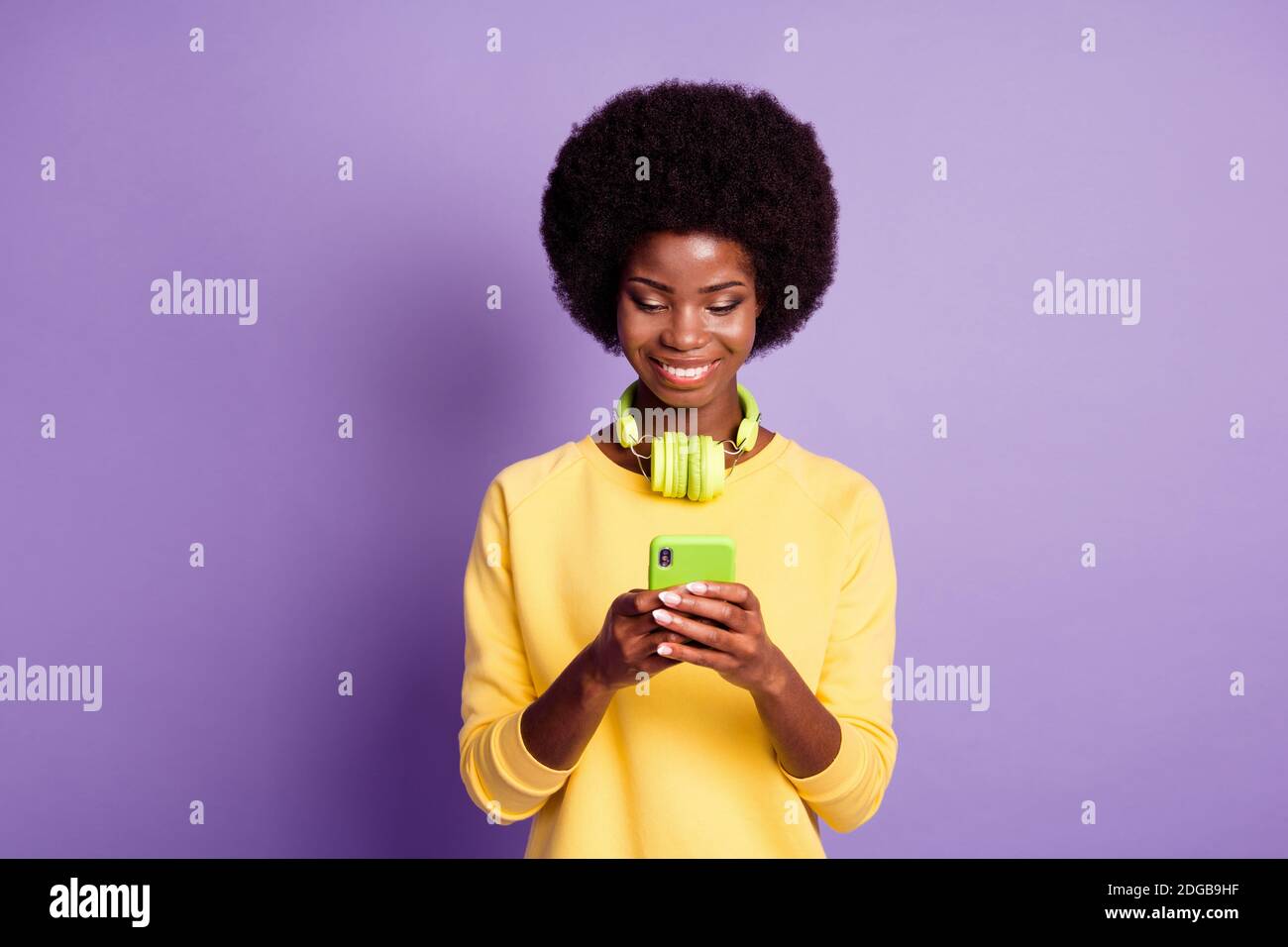 Photo of positive dark skin girl typing post on smartphone wear yellow ...