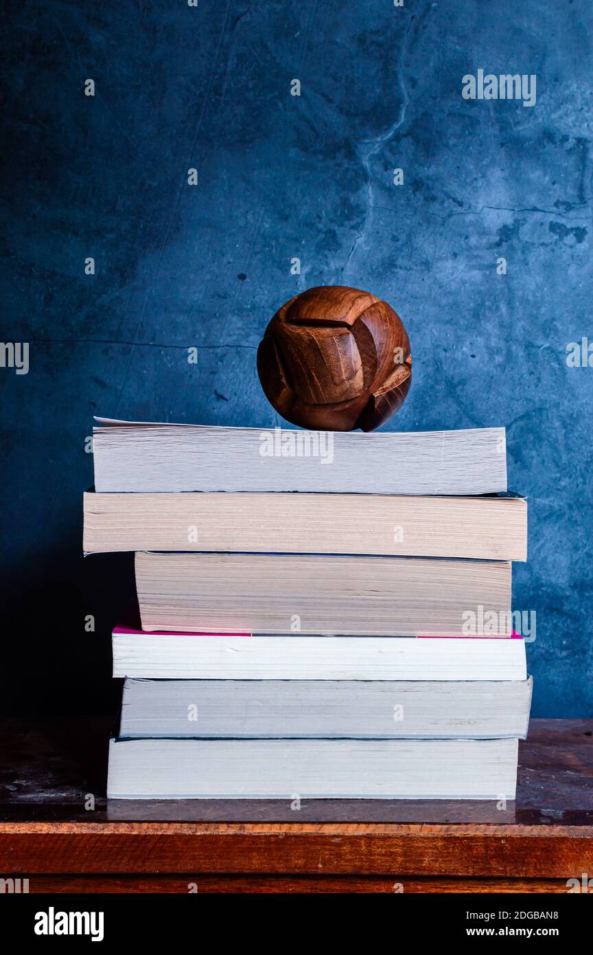 A sphere shaped puzzle made out of wood on top of a stack of book ...