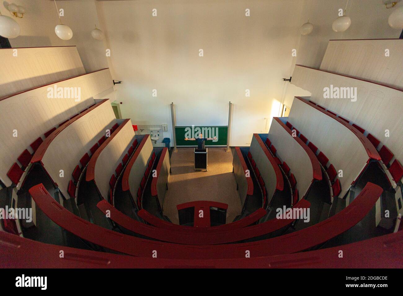 An empty hall in a German university. A man stands in front of the ...