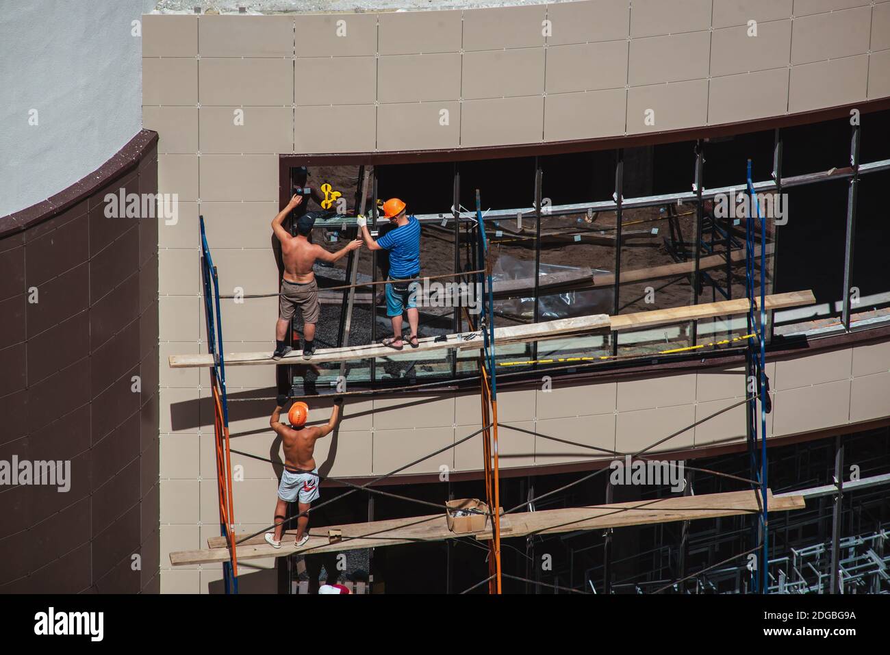 Window workers on a scaffold in construction yard on a building facade ...