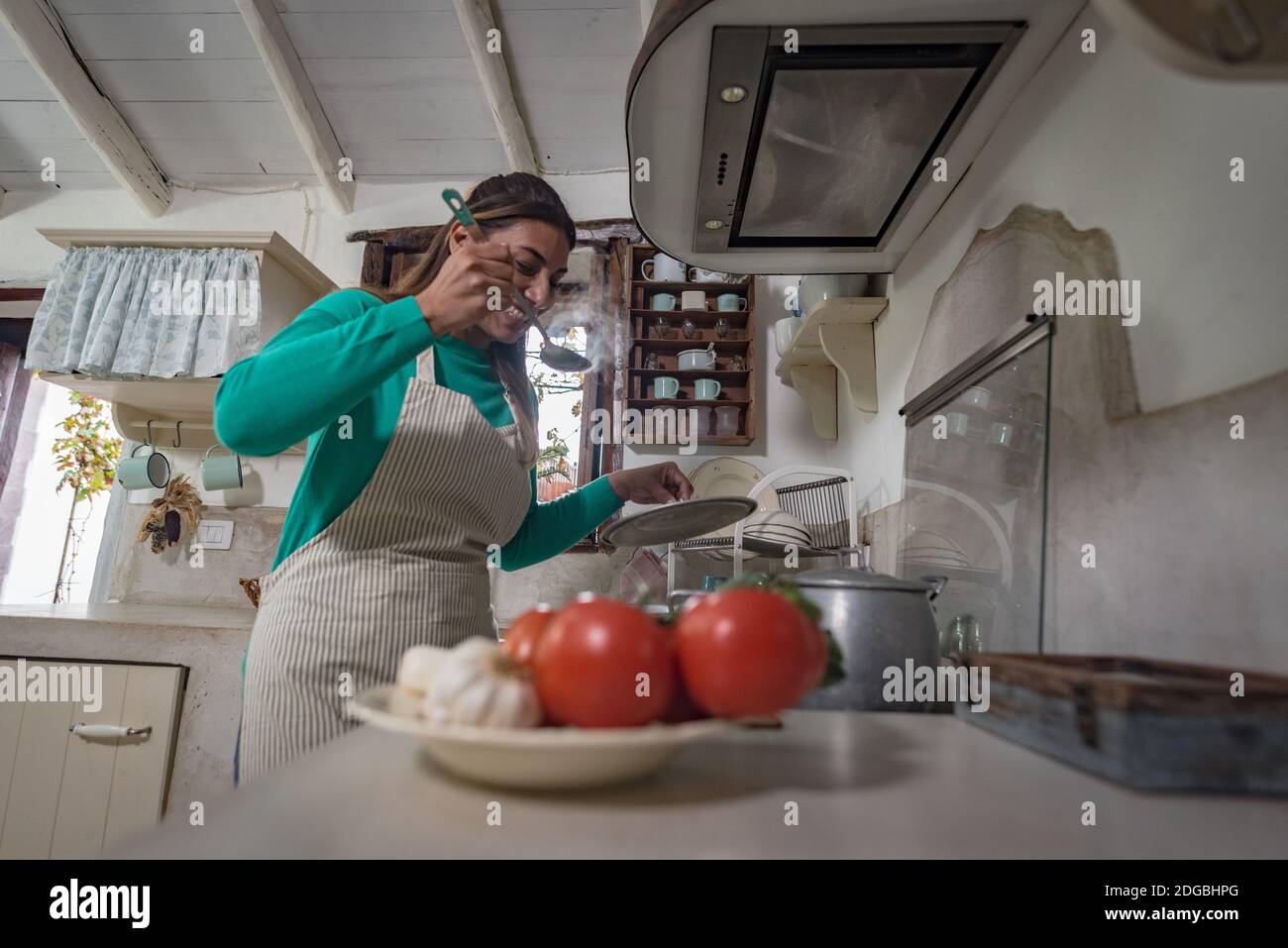 woman in a traditional vintage kitchen making a meal with old pots and ...