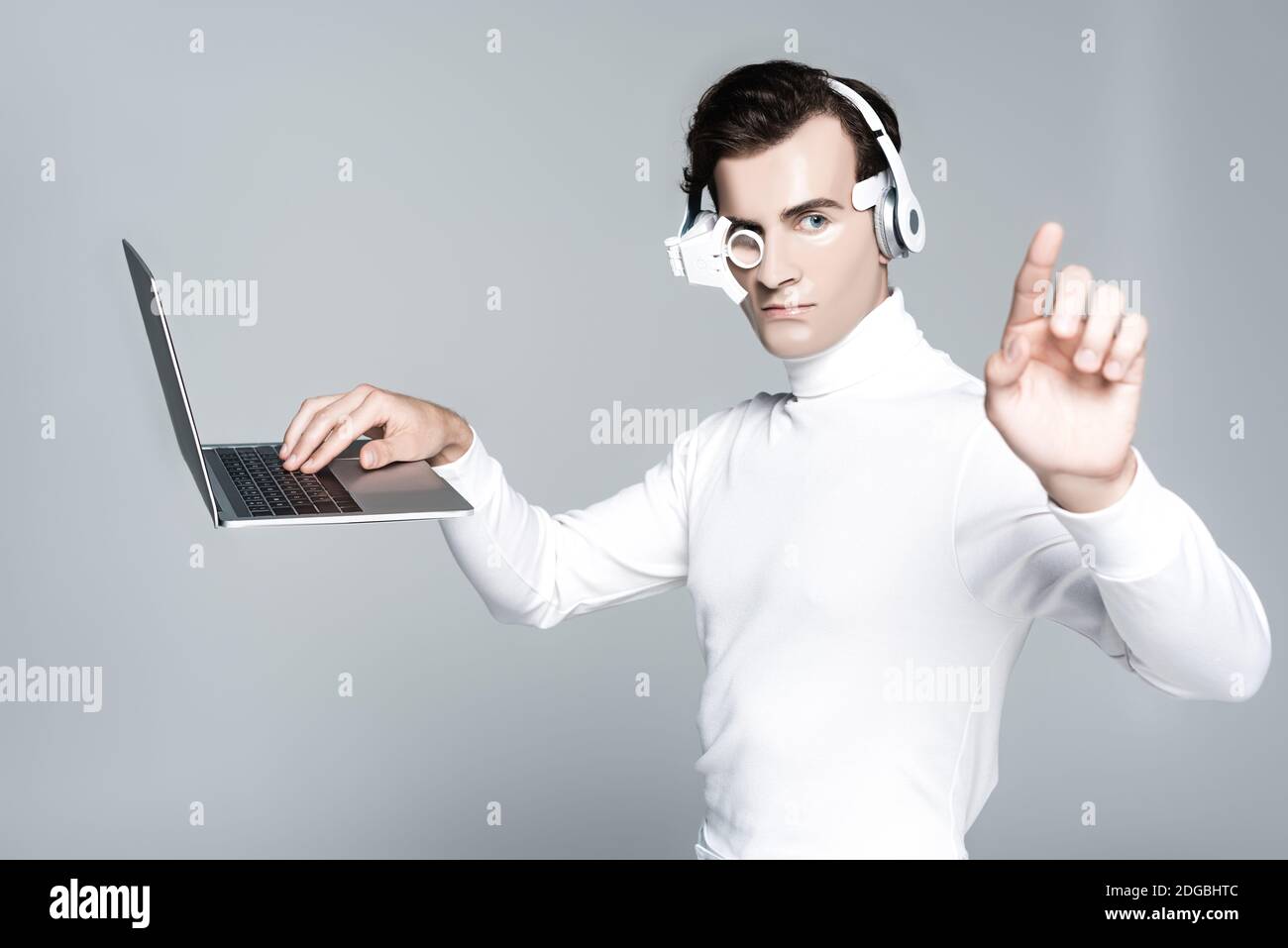 Cyborg man in headphones touching something while using laptop in air ...