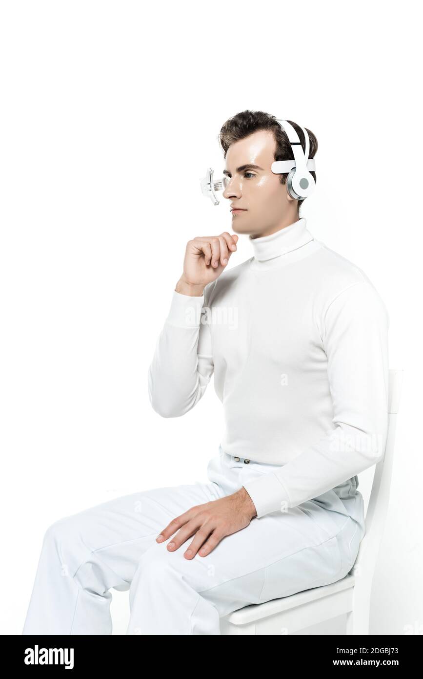 Cyborg man in eye lens and headphones with hand near chin sitting on ...