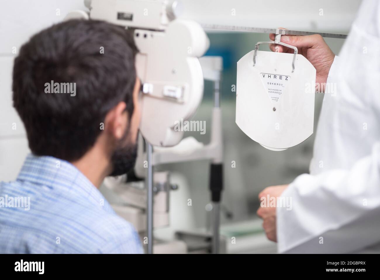 Male doctor ophthalmologist is checking the eye vision of handsome ...