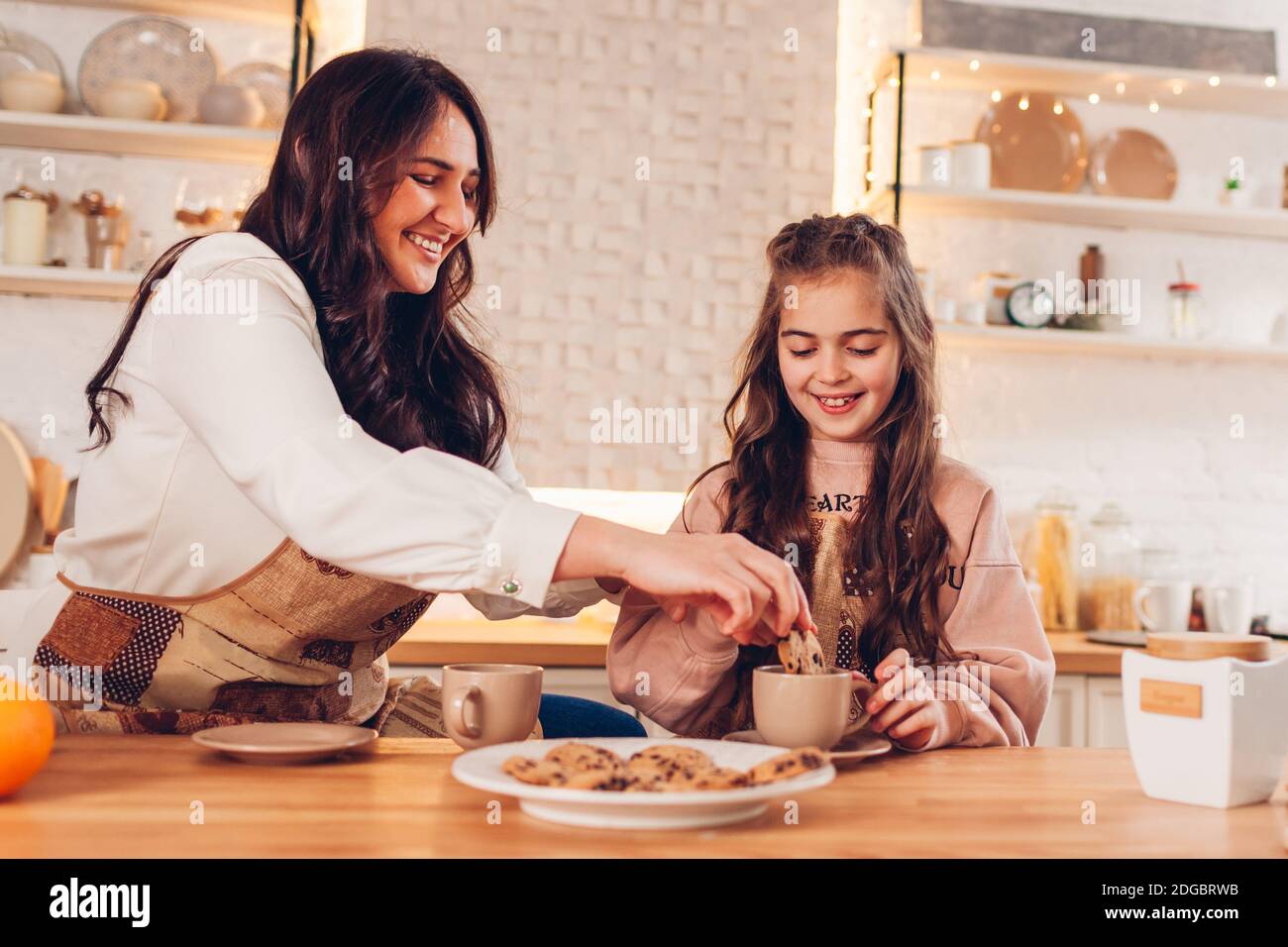 Family drinking tea with cookies at home. Mother and daughter laughing ...