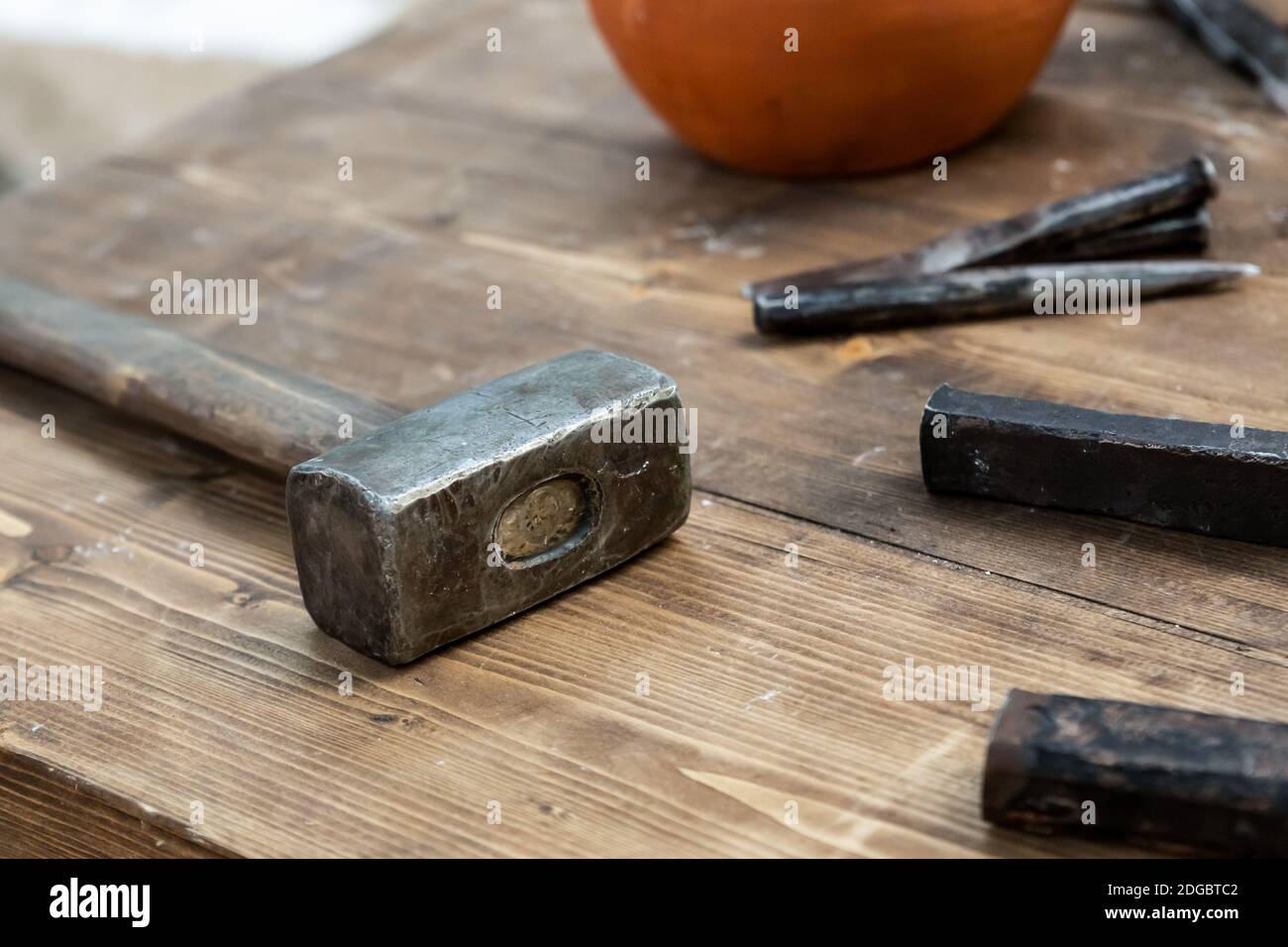 Old rusty weathered hammer lies on the table on the background of tools ...