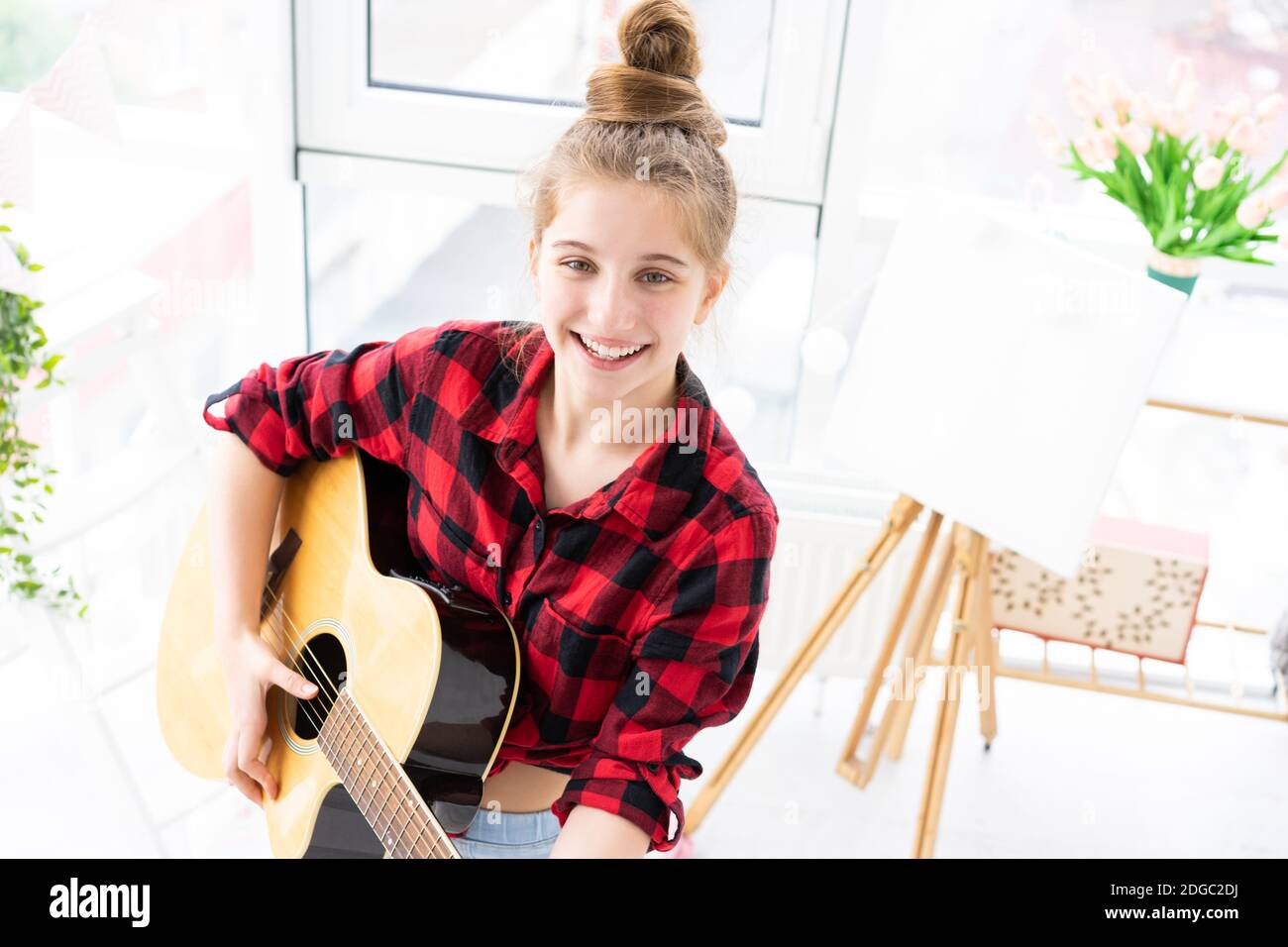 Happy teenage girl playing guitar in bright room Stock Photo - Alamy