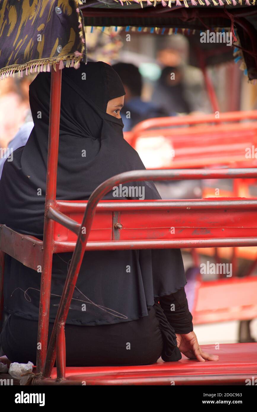 Muslim woman in black islamic attire riding in a rickshaw, Old Delhi ...