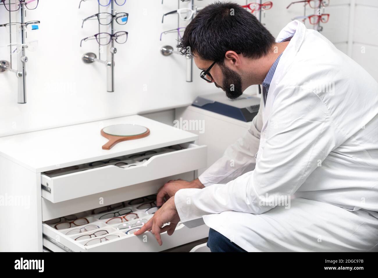 Ophthalmologist choosing glasses from a drawer in the optical store ...