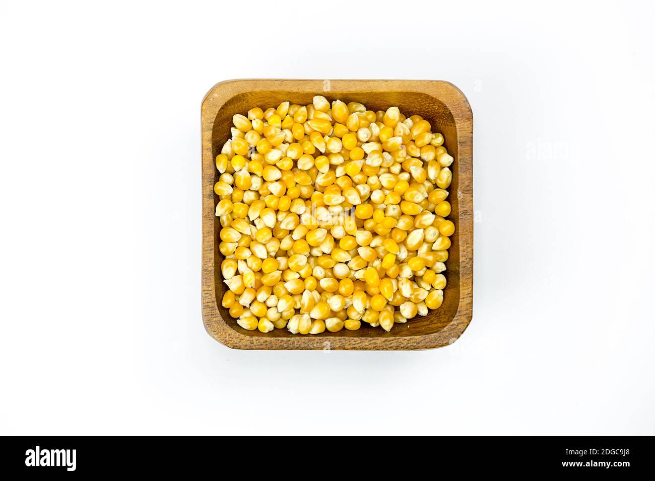 Seeds of golden corn popcorn in a wooden bowl close-up on a white ...