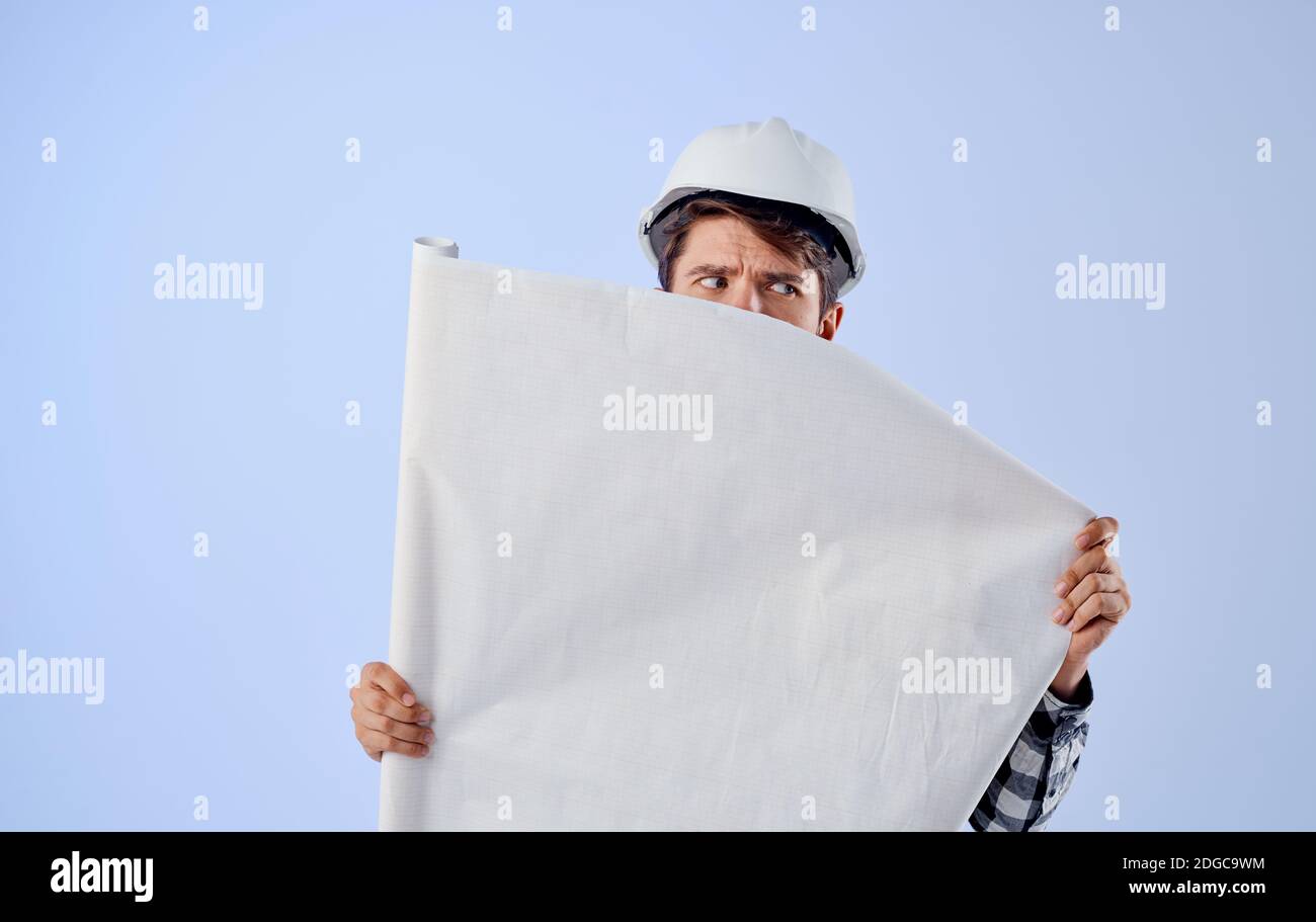 A man in a working uniform an engineer blueprints a project plan ...