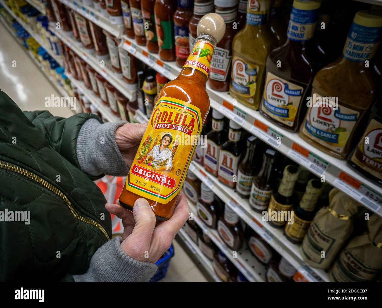 A discerning shopper chooses a bottle of Cholula brand hot sauce in a ...
