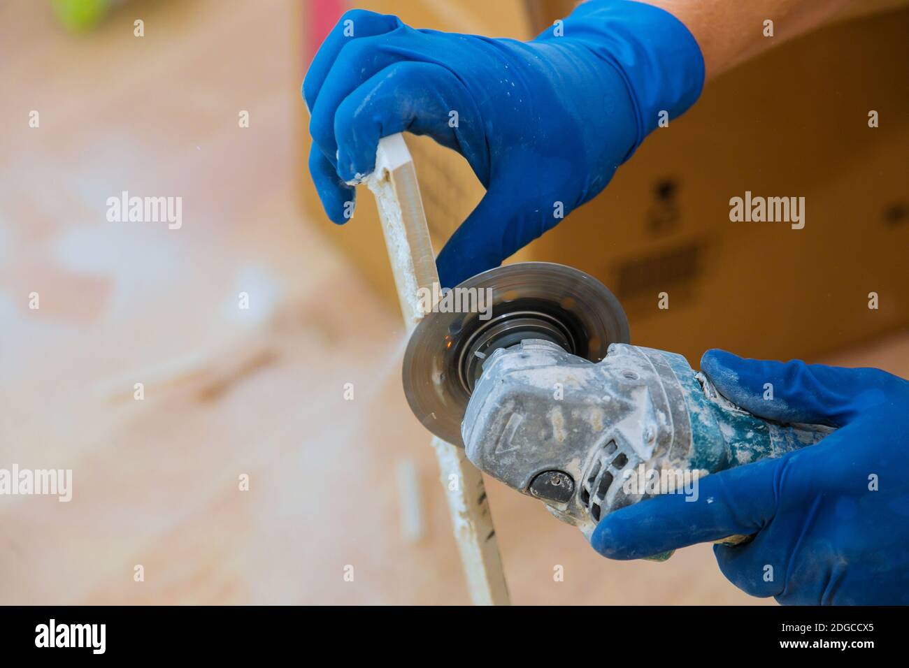 Worker cutting a tile using grinder at construction trimming tiles ...
