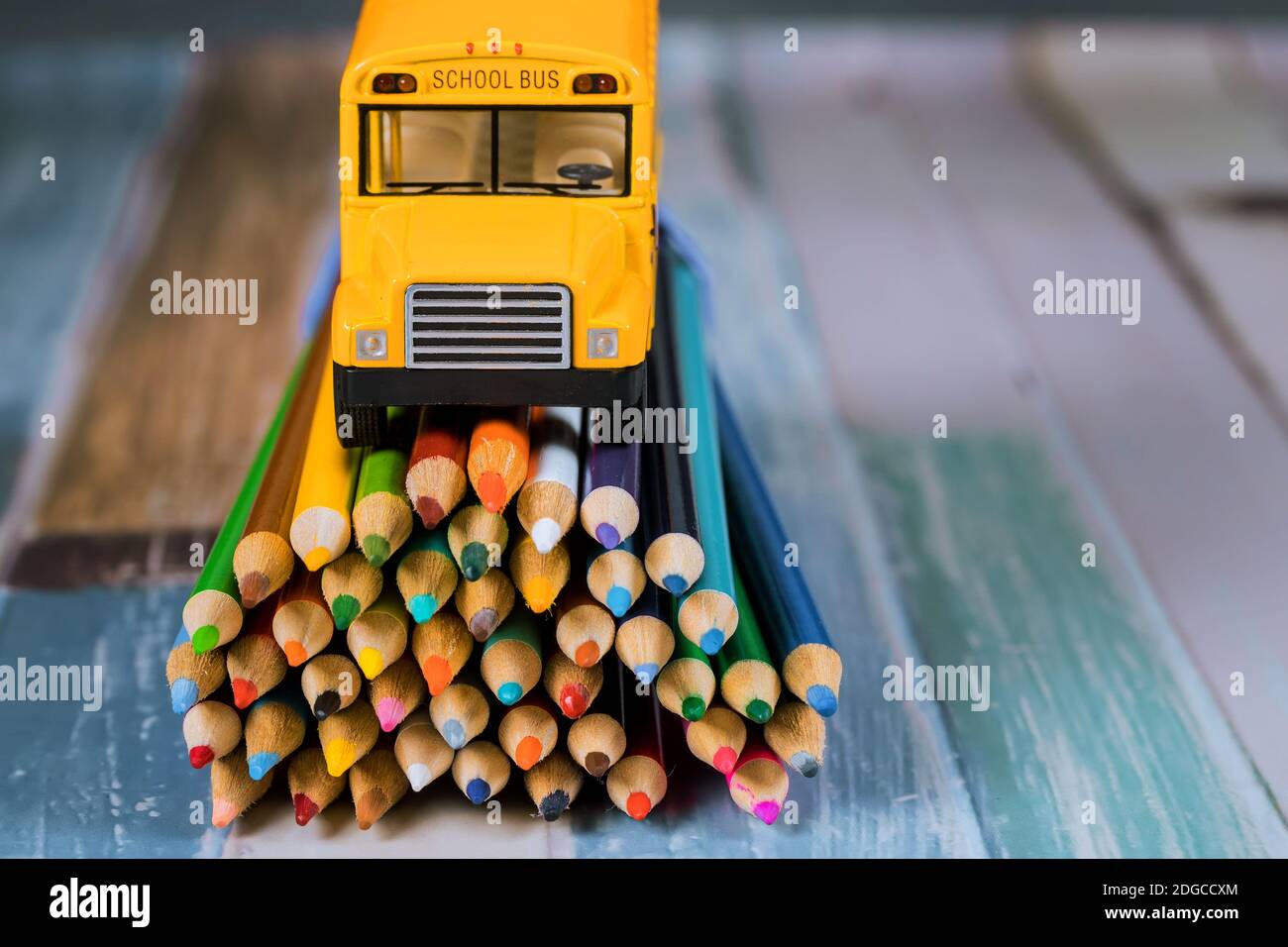 Toy yellow bus on bunch of colored pencils Stock Photo - Alamy