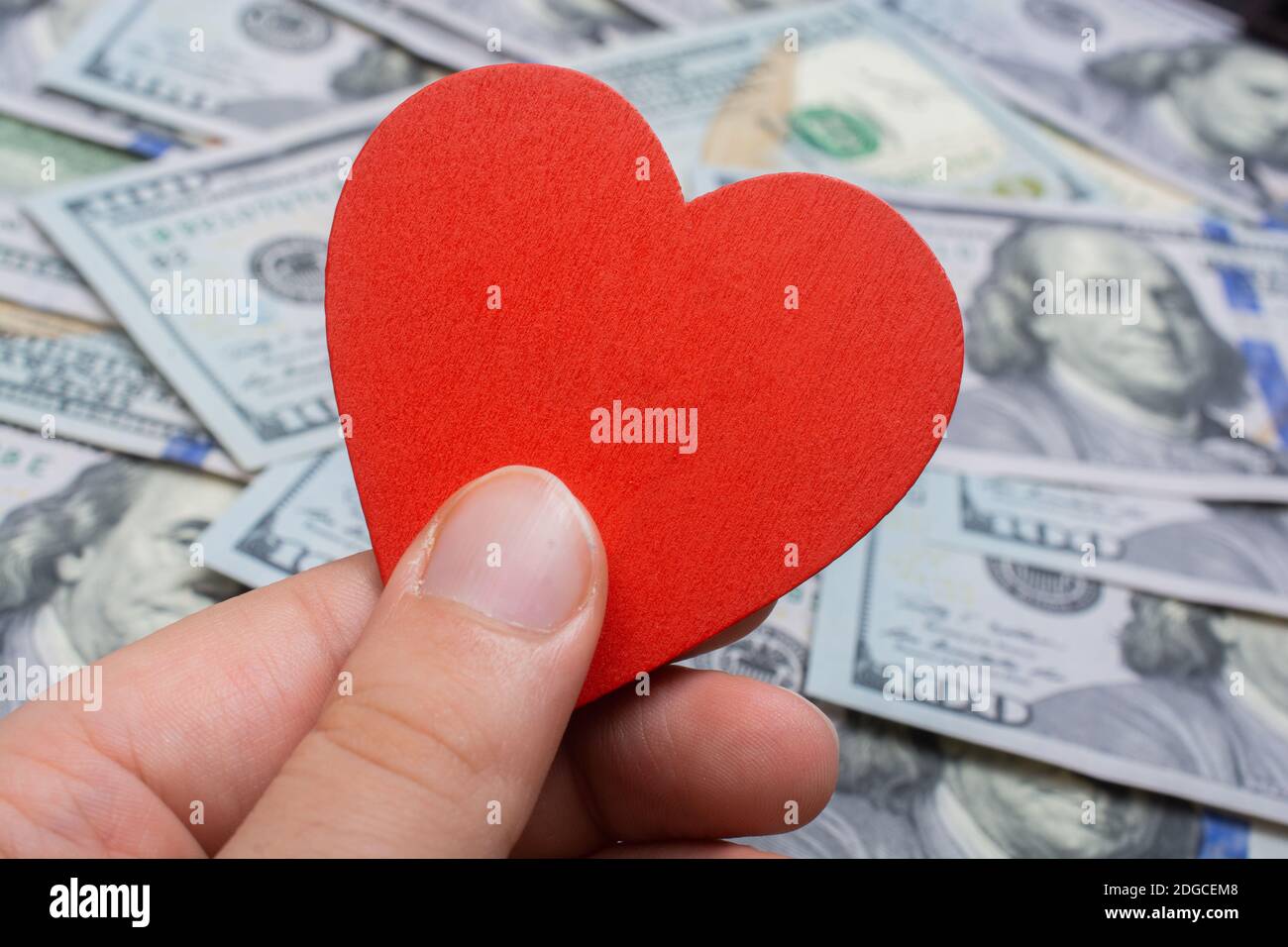 Red heart on hand on dollar bills. Concept of selling love for money ...