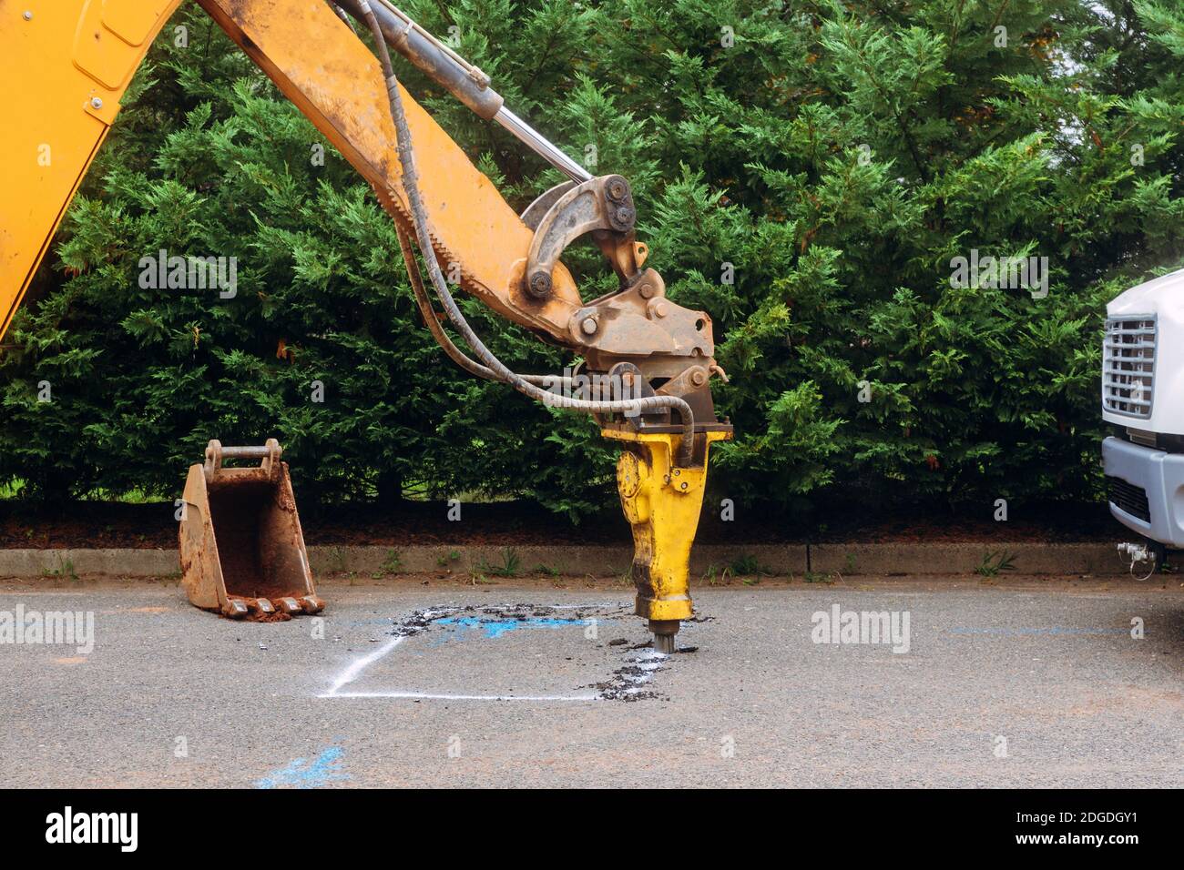 Large jackhammer crushing asphalt paving during road construction works ...