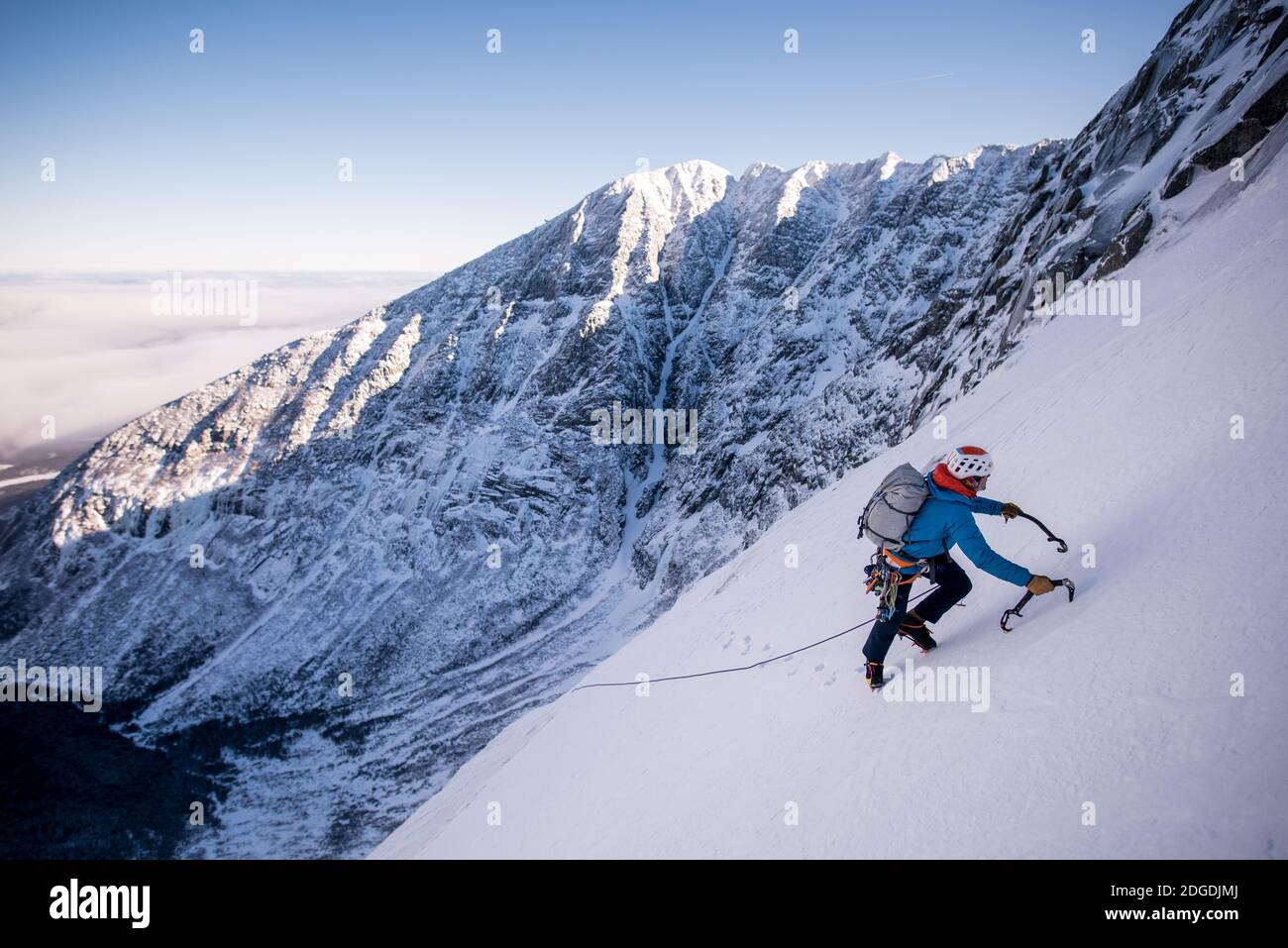 Alpine climber ascending steep snow with mountains behind Stock Photo ...