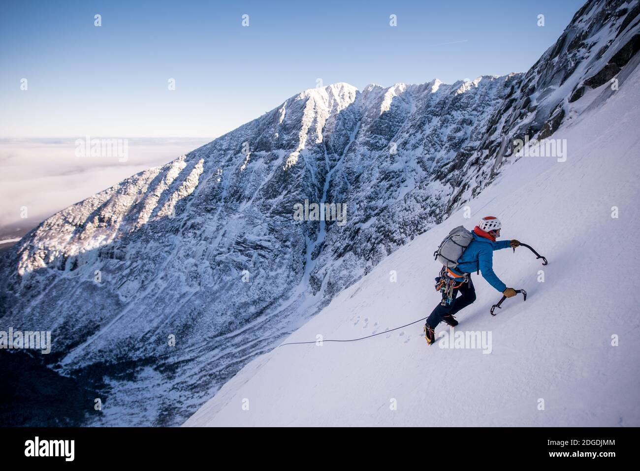 Alpine climber ascending steep snow with mountains behind Stock Photo ...