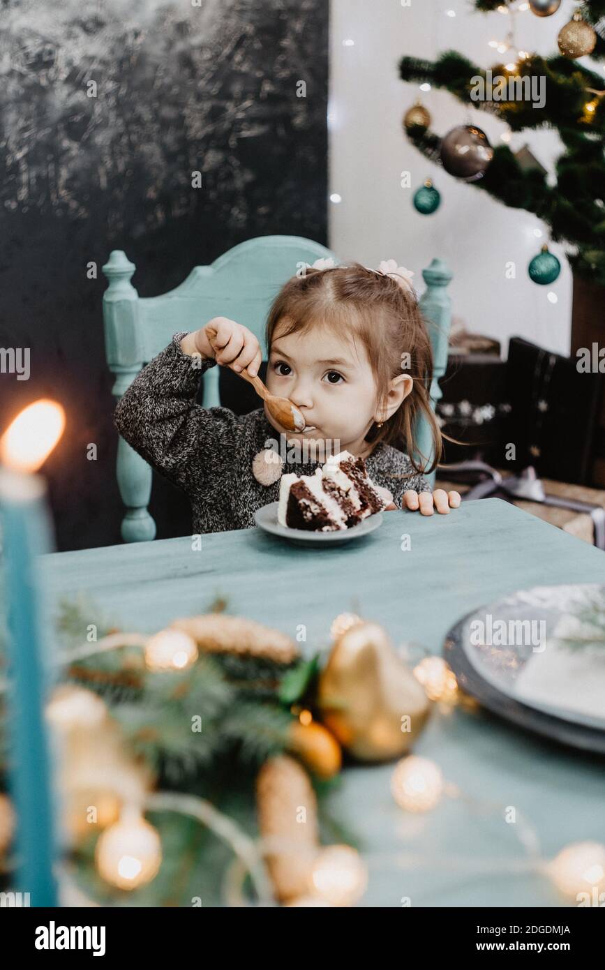Little girl eating christmas cake on a set table Stock Photo - Alamy