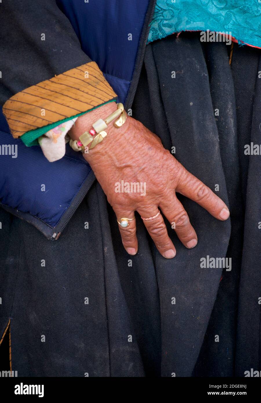 Hand of a Ladakhi woman in traditional attire visiting Karsha monastery ...