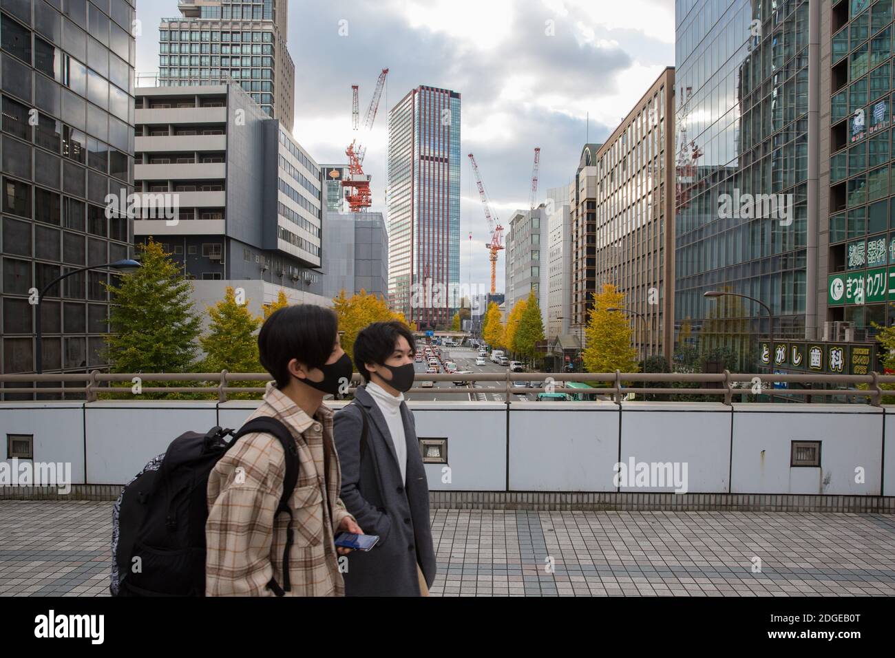 Men wearing face masks walk on a pedestrian bridge in Minato-ku, Tokyo ...