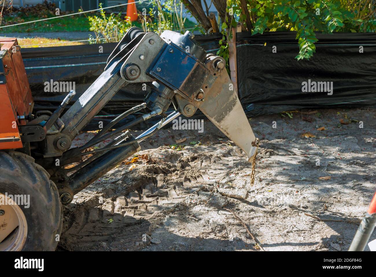 Small tractor is digging in the ground lay water pipe for irrigation ...