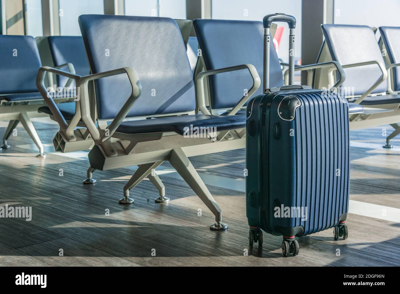 Small plastic travel suitcase in the airport hall Stock Photo - Alamy