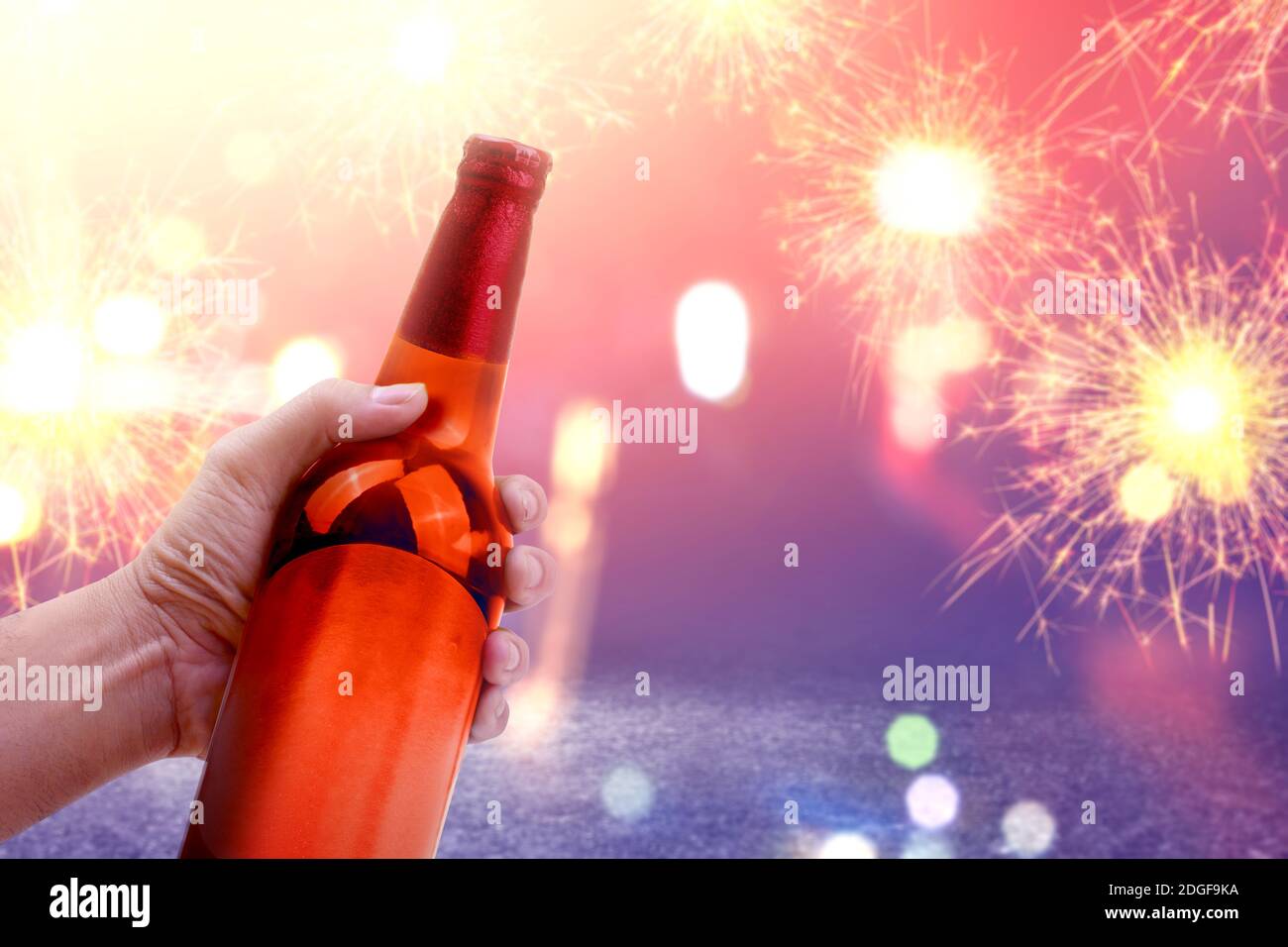 Hand holding beer bottle with fireworks background Stock Photo - Alamy