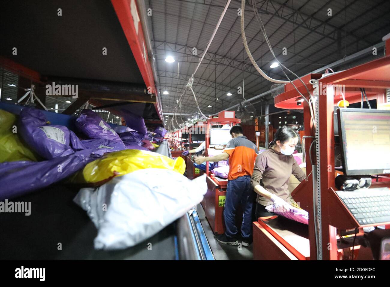 Workers sort and arrange deliveries by a delivery belt in at a ...