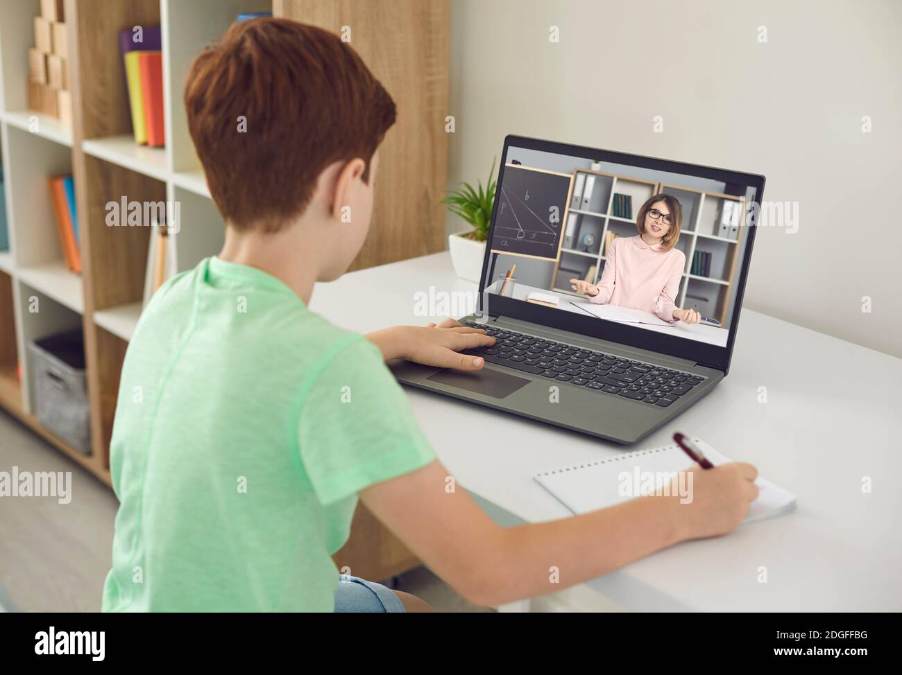 Boy pupil sitting at home and making notes during online lesson Stock ...