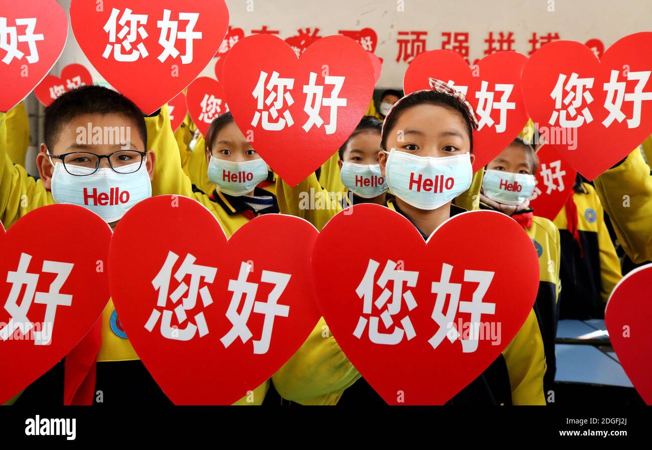 Pupils wear masks with Hello written on them and hold signs in their ...