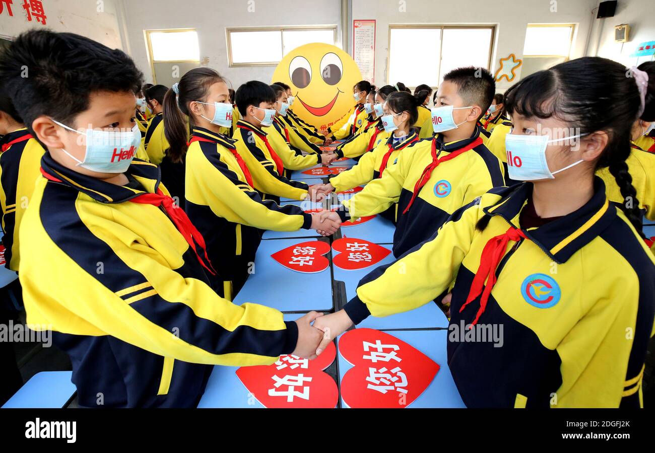 Pupils wear masks with Hello written on them and hold signs in their ...