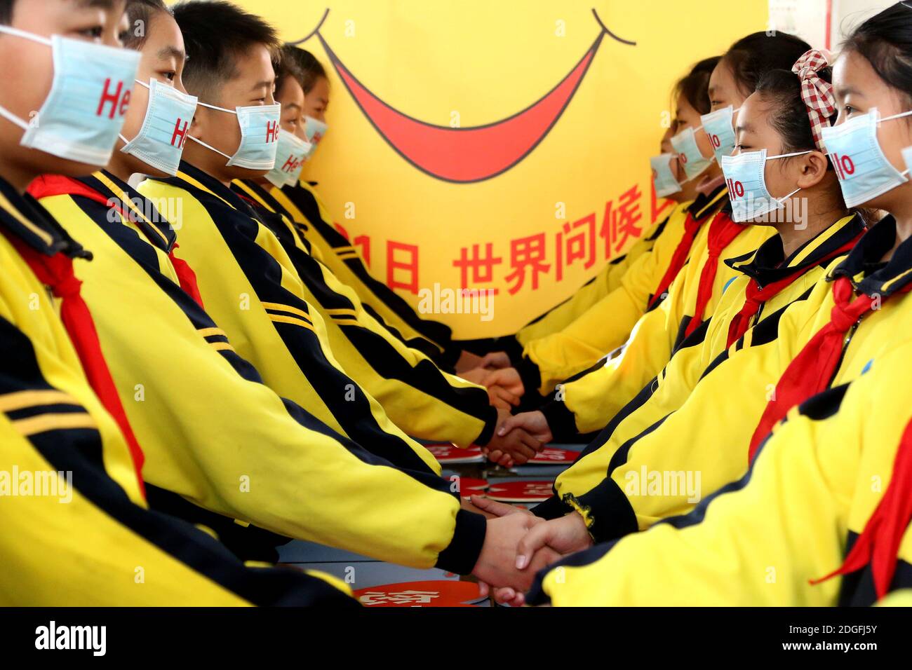 Pupils wear masks with Hello written on them and hold signs in their ...