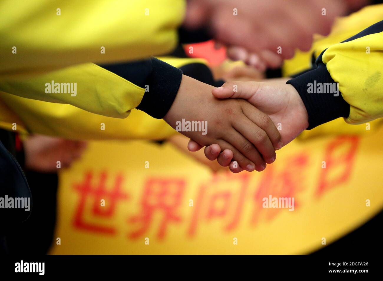 Pupils wear masks with Hello written on them and hold signs in their ...