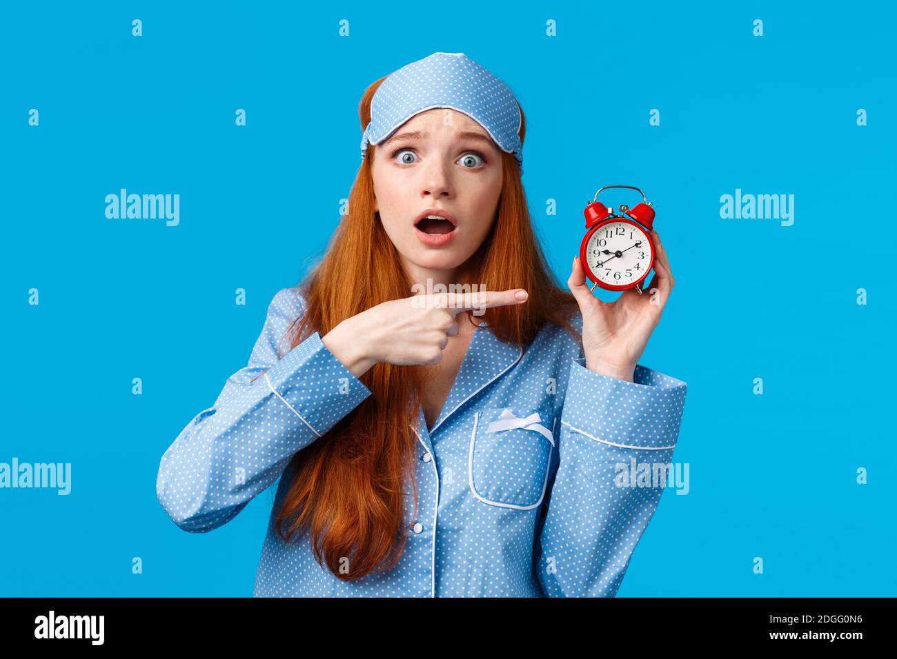 Shocked and concerned, worried cute redhead girl pointing at alarm ...
