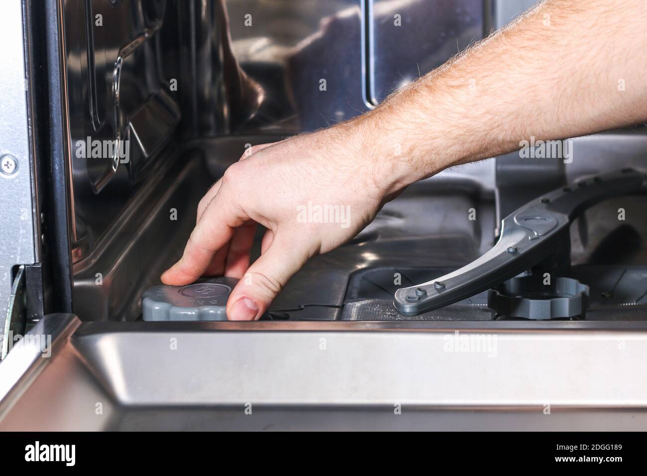 Man opens the container for salt in the dishwasher and fills there a ...